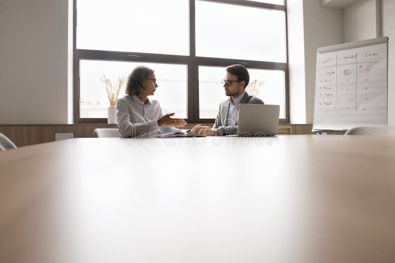 Two Business Partners Focused in Conversation at Conference Table Stock ...