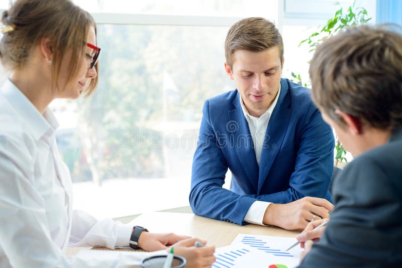 Business People Analyzing Financial Results on Graphs Around the Table ...