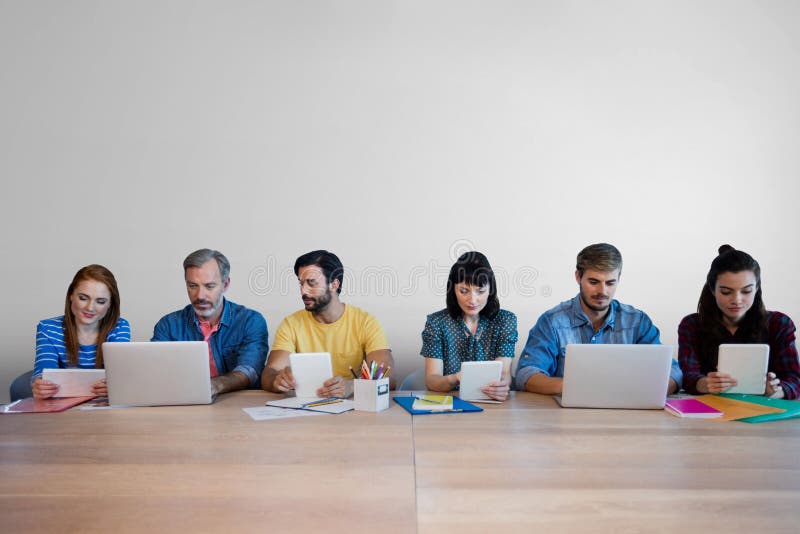 Business People at a Desk Looking at Computers and Tablets Against ...