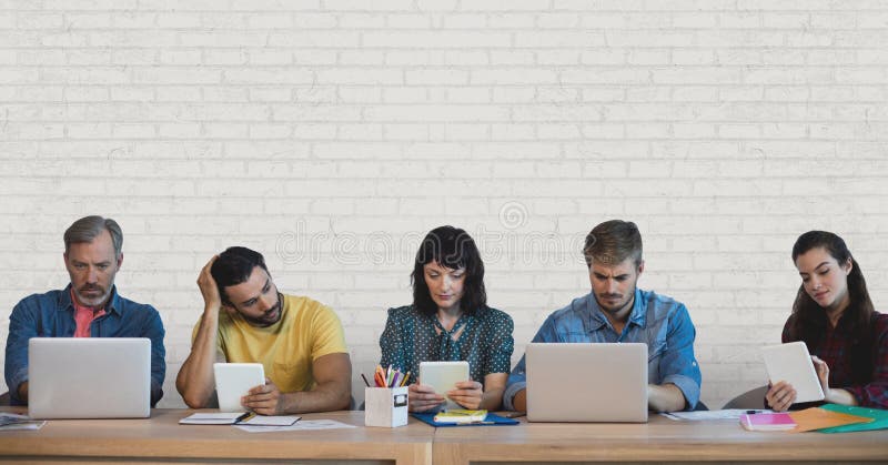 Business People at a Desk Looking at Computers and Tablets Against ...