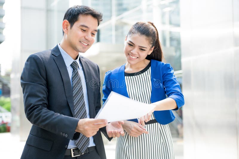 Business People Discussing Document while Walking Outdoors Stock Image ...