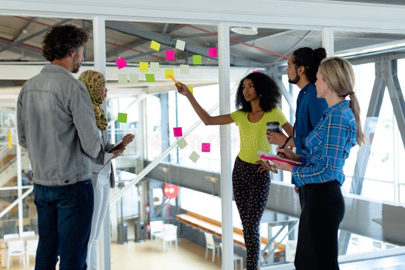 Business People Discussing Over Sticky Notes on Glass Wall in a Modern ...