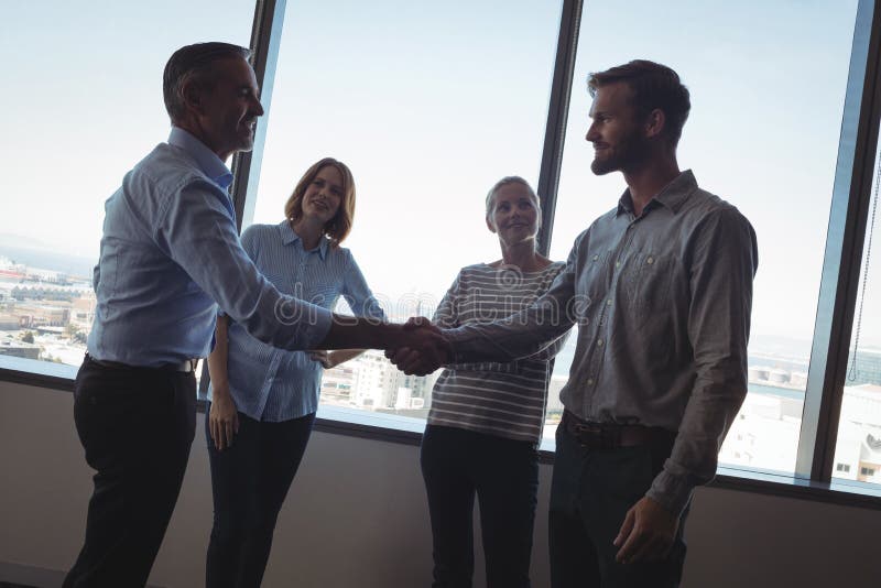 Business People Shaking Hands Against Windows at Office Stock Image ...