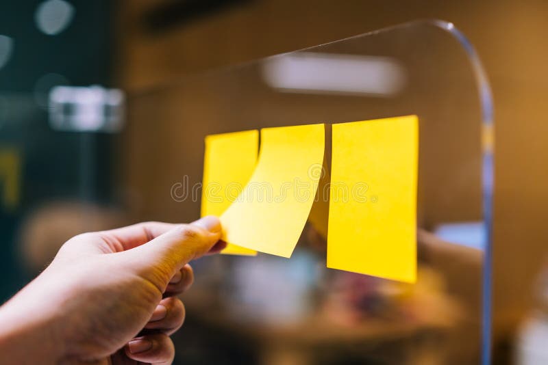 Business People Using Sticky Note on Plexiglass Separators To Share ...
