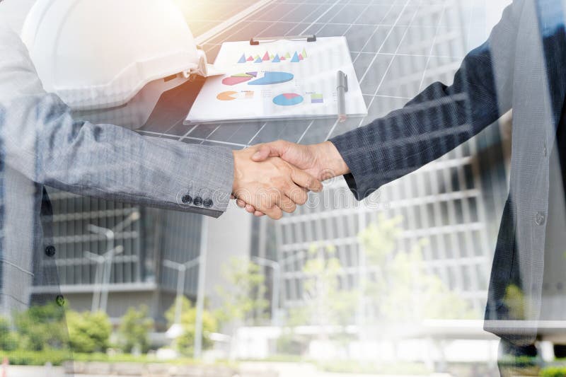 Business Professionals Shaking Hands Over Solar Panels Reflecting a ...
