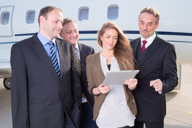 Business Team in Front of Corporate Jet Looking at Tablet Comput Stock ...