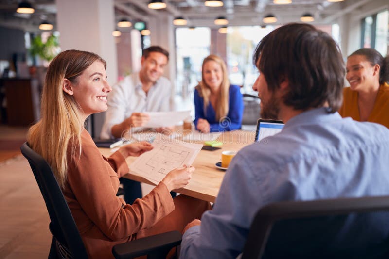 Business Team Having Meeting Sitting Around Table in Modern Open Plan ...