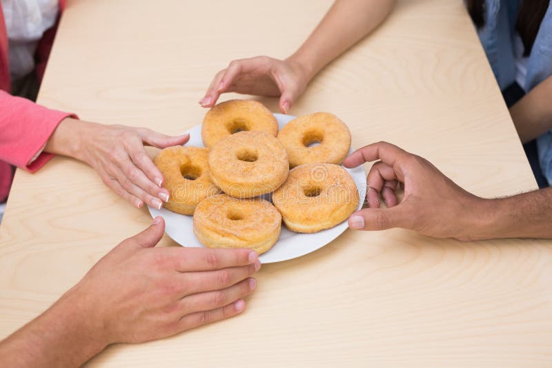 Business Team Reaching for Doughnuts on Table Stock Image - Image of ...