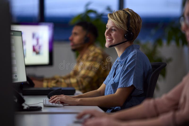 Business Team Wearing Headsets Working Late at Customer Support Centre ...