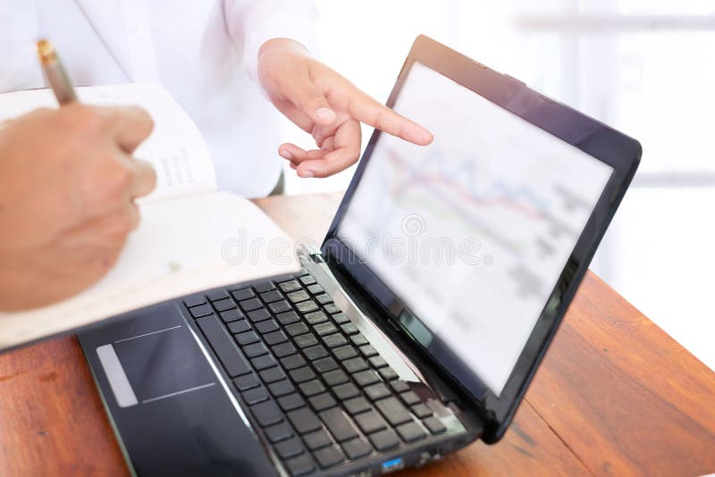 Business Teamwork Discussing Data with a Finance Graph on Laptop ...