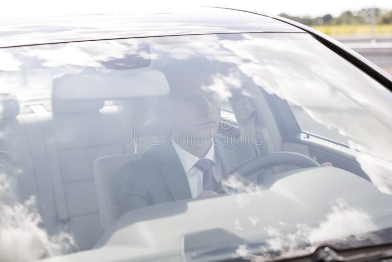 Serious Businessman Driving Car with Reflection of Clouds on Windshield ...