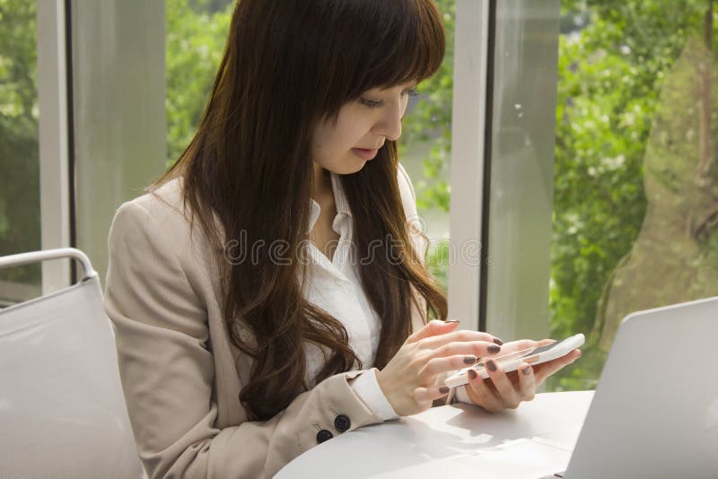 Business Woman with Mobile Phone Working in Front of Laptop Computer ...