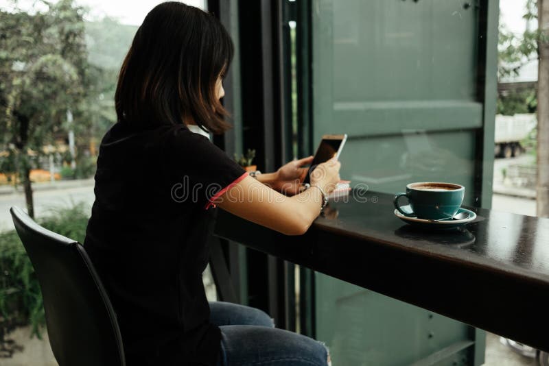 Business Woman Sit Alone In A Restaurant And Play Smart Phone O Stock