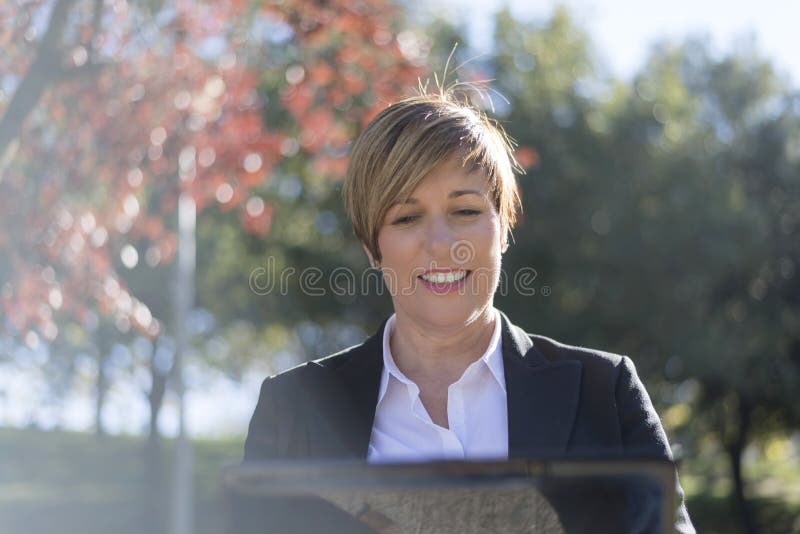 Business Woman Sitting In The Park On A Bench Working With A Laptop