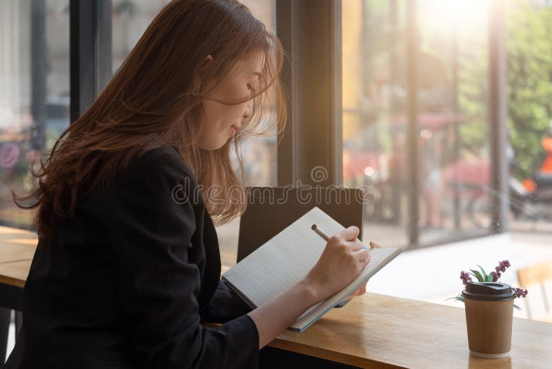 Business Woman Taking Notes in a Book with Laptop on Table Stock Image ...