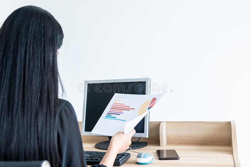 Business Woman Using Computer To Analyze Performance Data from Paper ...