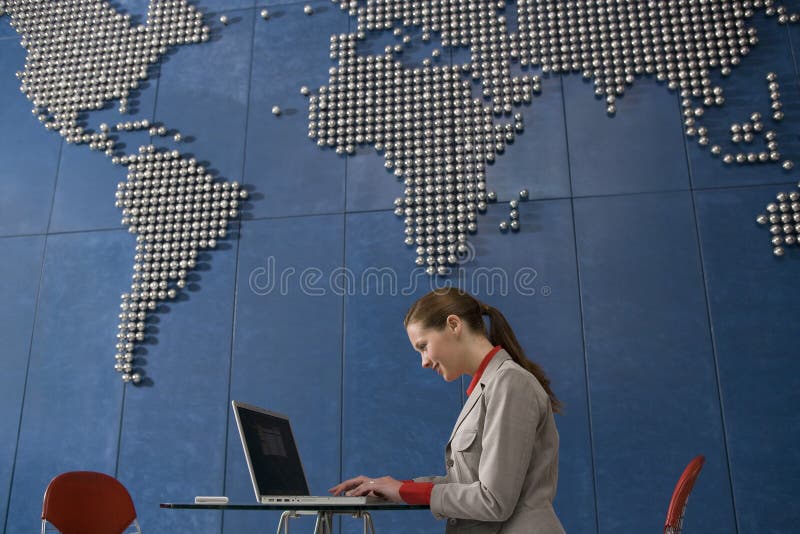 Business Woman Using Laptop in Office with World Map on Wall Stock ...
