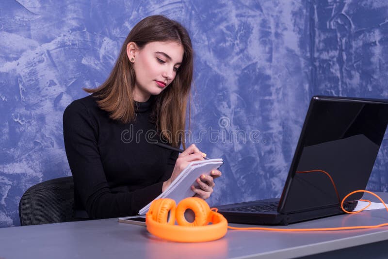 Business Woman Working at a Laptop and Writing in a Notebook, Distant ...
