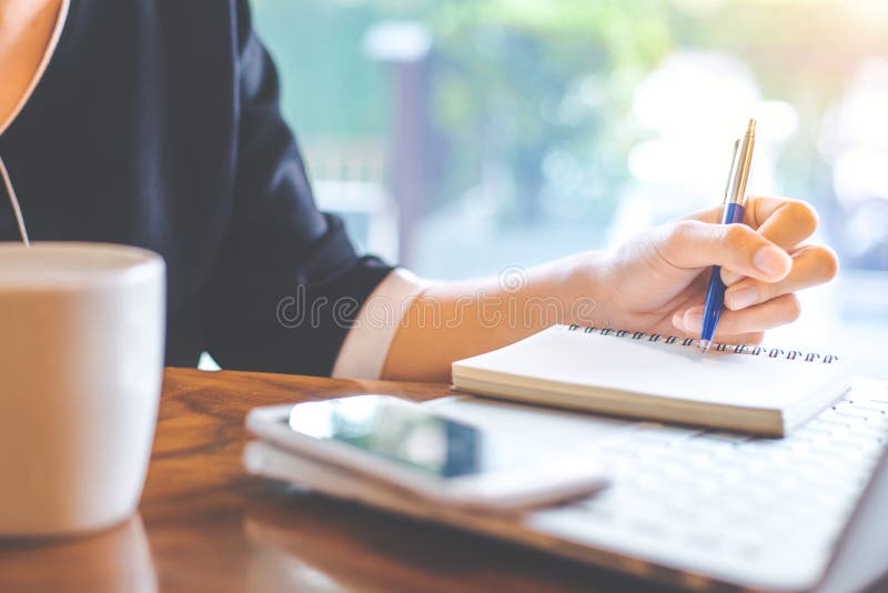 Business Women Hand are Working at a Notebook Computer and Taking Notes ...