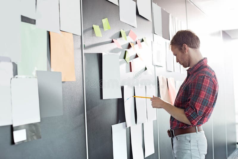 Businessman Analyzing Documents on Wall at Creative Office Stock Image ...