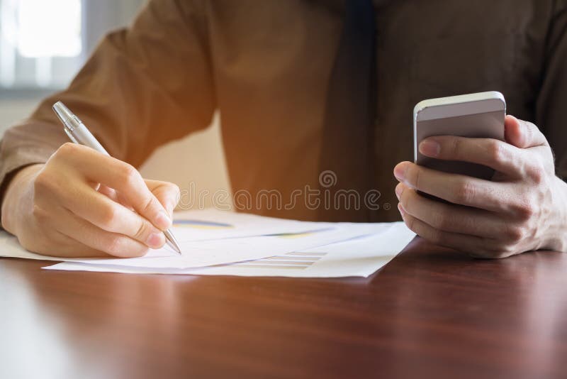 Businessman Analyzing Graph Document with Laptop and Using Cell Phone ...