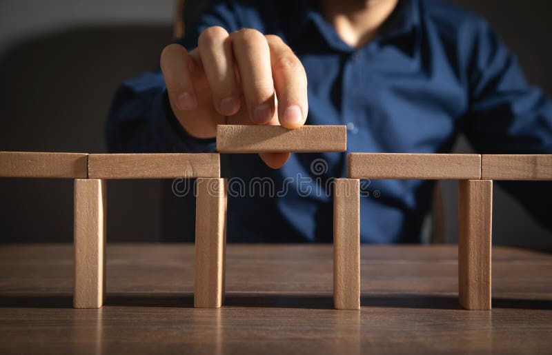 Businessman Assembling a Bridge Made from Wooden Blocks Stock Image ...