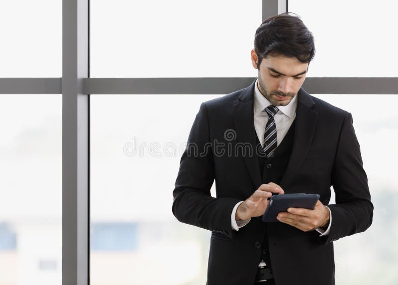 Businessman in Black Suit Holding and Using Tablet Computr in Office ...