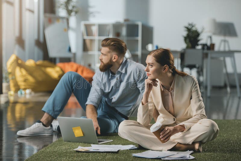 Businessman and Businesswoman Sitting on Floor and Using Laptop Stock ...