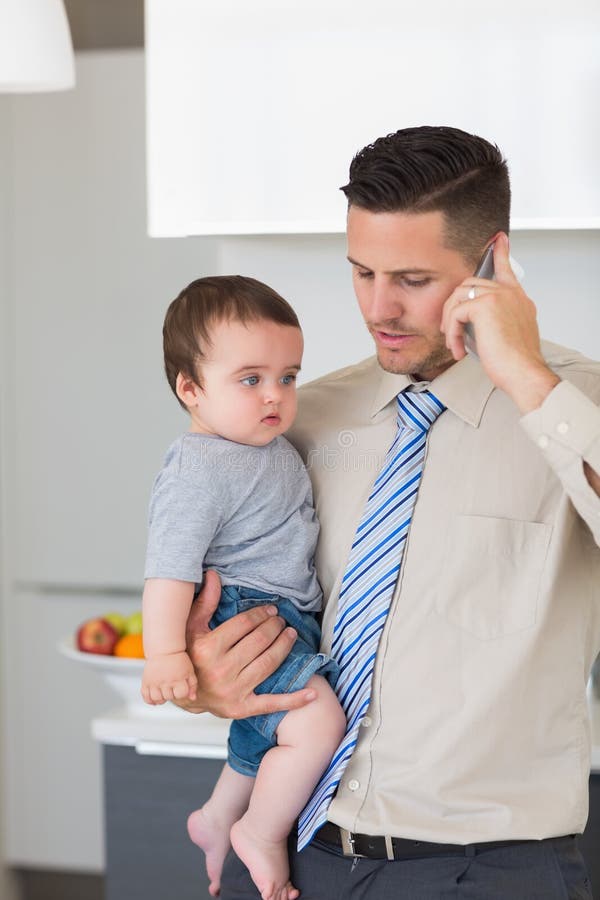 Businessman Carrying Baby Boy while Using Mobile Phone Stock Photo ...