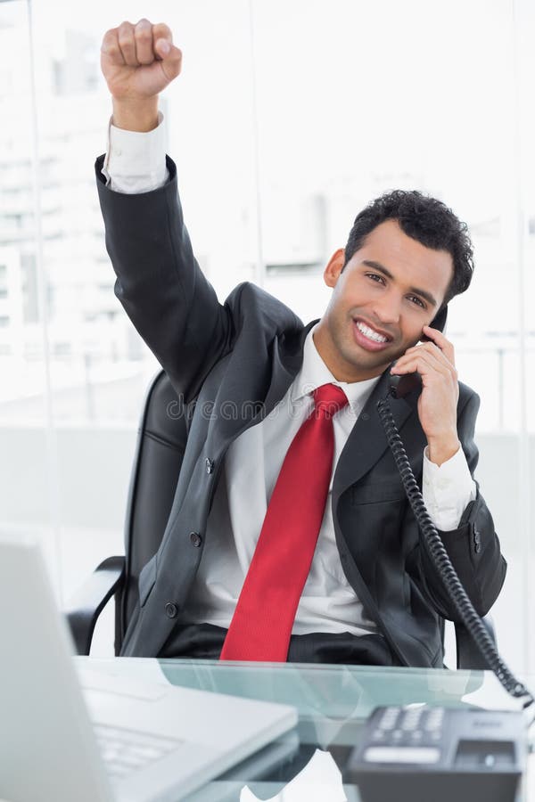 Businessman Cheering while on Call at Office Desk Stock Photo - Image ...