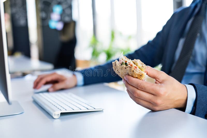 Businessman at the Desk with Computer Eating Lunch. Stock Photo - Image ...