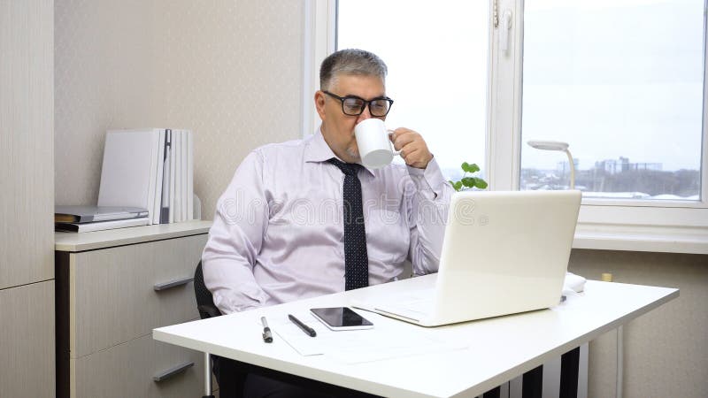 Businessman Drinking Tea and Working on Computer in Office Stock Photo ...