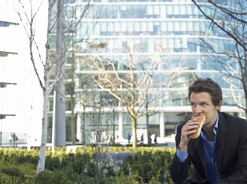 Businessman Eating Sandwich in Front of Office Building Stock Image ...