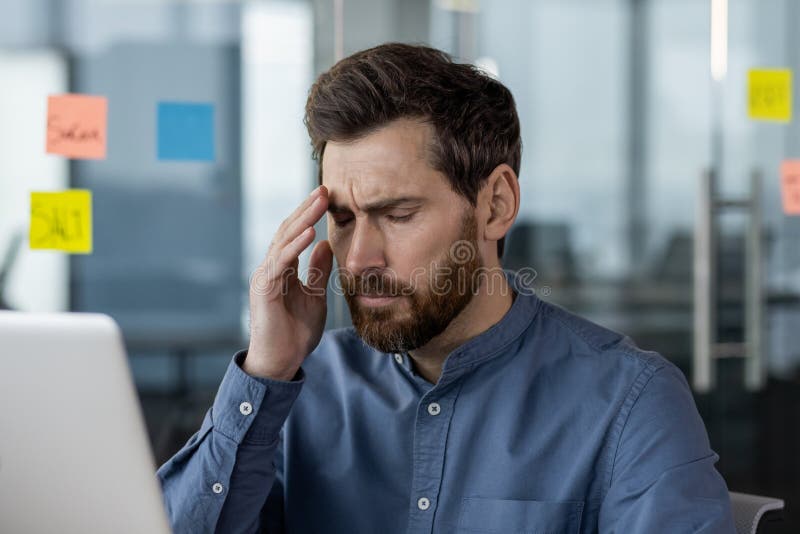 Businessman Experiencing Headache while Working on Computer in Modern ... Businessman Experiencing Headache while Working on Computer in Modern ...