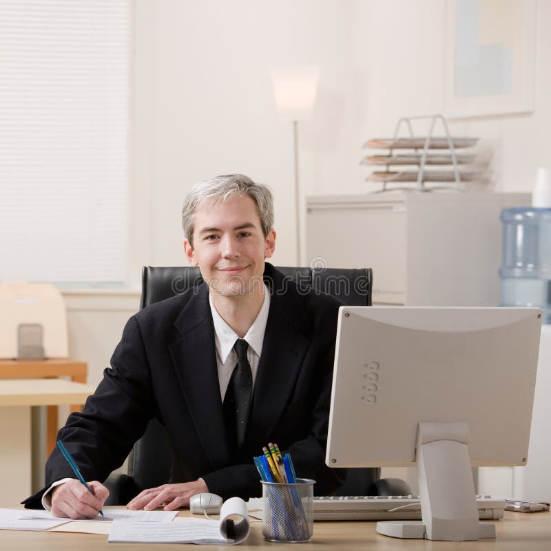 Businessman Filling Out Paperwork at Desk Stock Photo - Image of ...