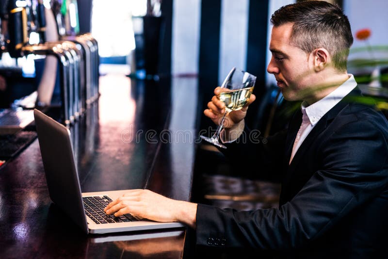 Businessman Getting a Glass of Wine and Using Laptop Stock Photo ...