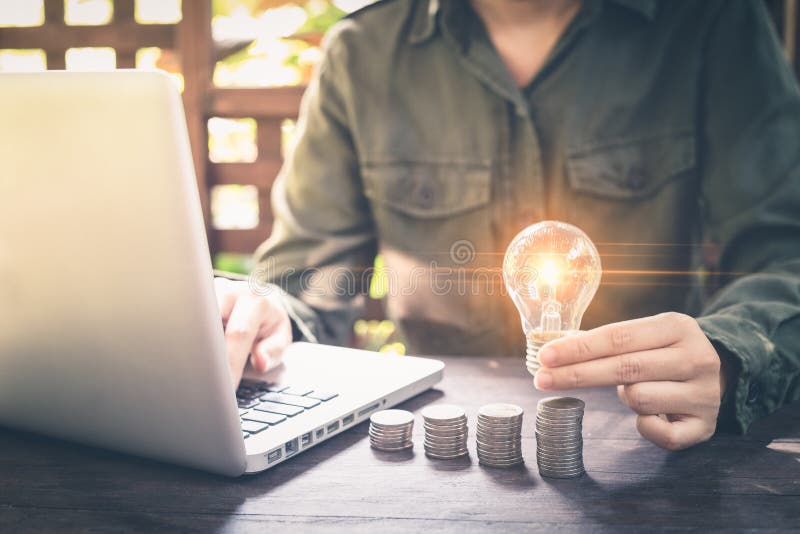 Businessman Hand Holding Lightbulb on Stack Coins, and Working with ...