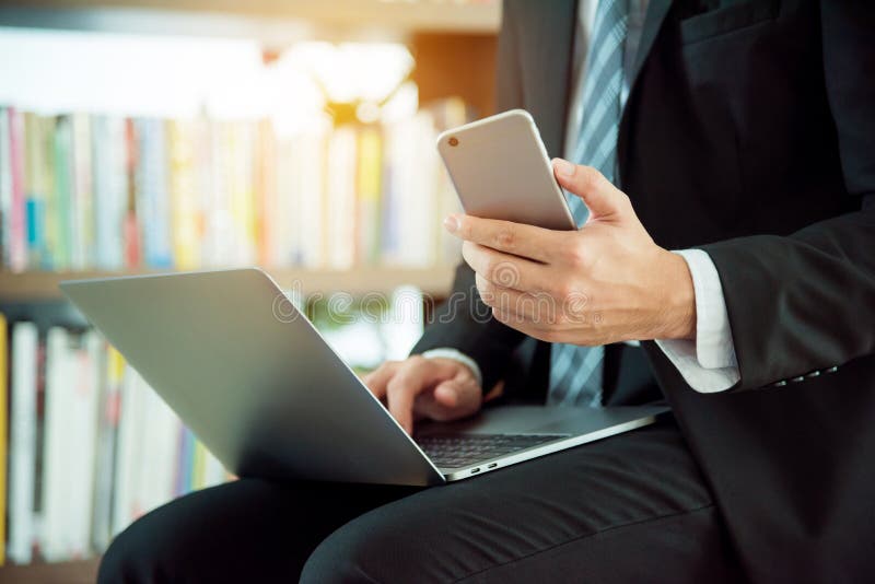 A Businessman Holding Phone while Using Laptop Computer Stock Image ...