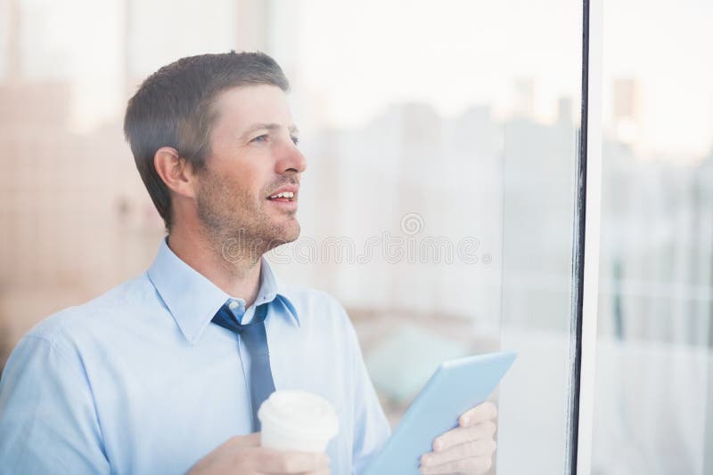 Businessman Holding Disposable Cup and Tablet Looking Out the Window ...