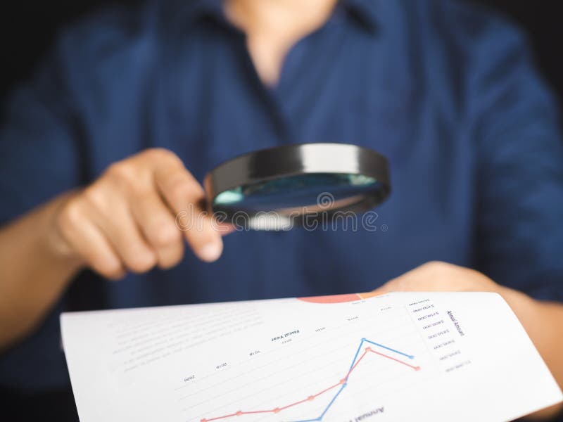 Businessman Holding a Magnifying Glass Looking at the Report for ...