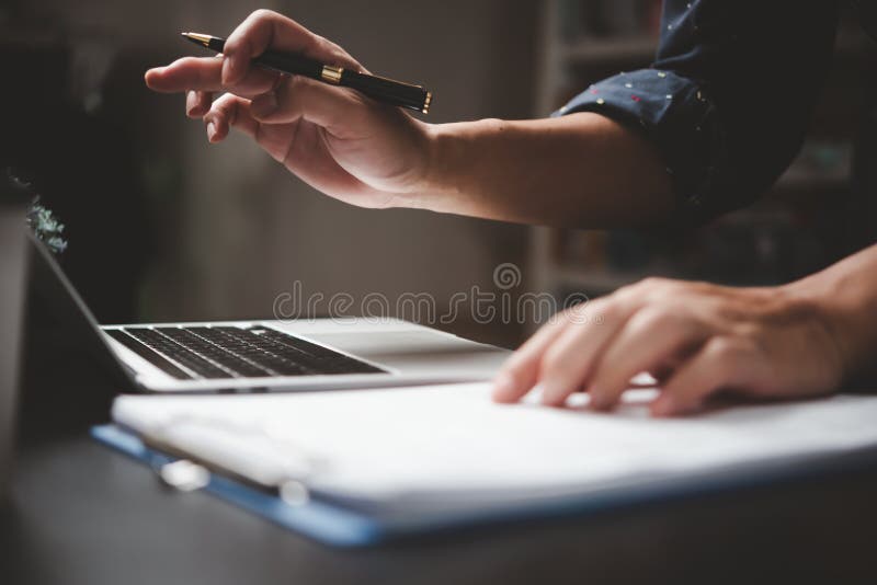 Businessman Holding Pen and Paperwork with Computer Laptop on Desk ...