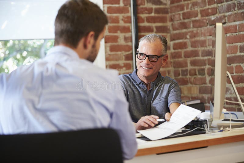Businessman Interviewing Male Job Applicant in Office Stock Image ...