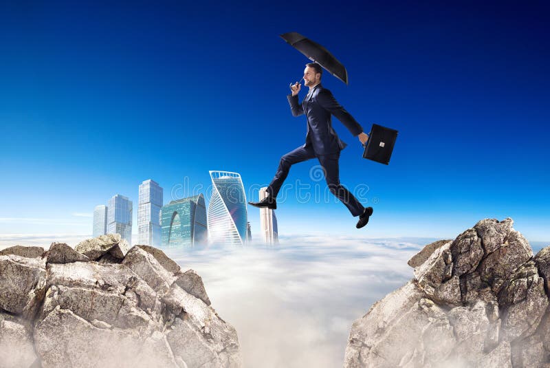 Businessman Jumping Over a Cliff with Umbrella Over Blue Sky Background ...