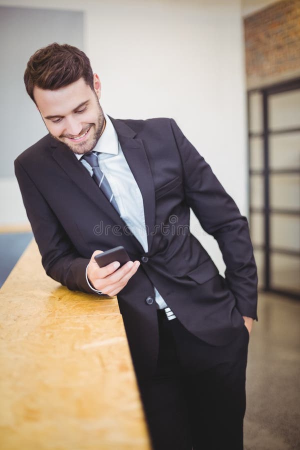 Businessman Looking in Cellphone while Leaning on Counter Stock Photo ...