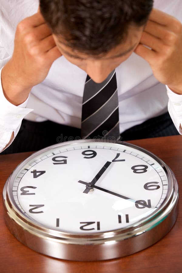 Businessman Looking at Clock in Office with Head in Hands Stock Photo ...