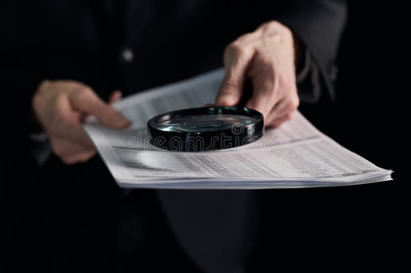 Businessman Looking through a Magnifying Glass To Documents Note in the ...
