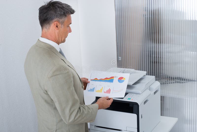 Businessman Looking at Paper with Graphs by Color Printer Stock Image ...