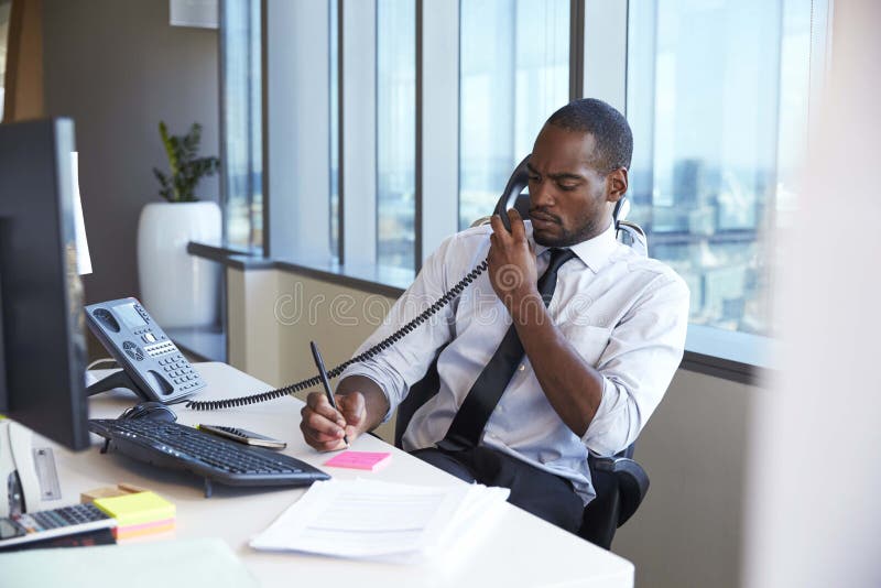 Businessman Making Phone Call Sitting at Desk in Office Stock Photo ...