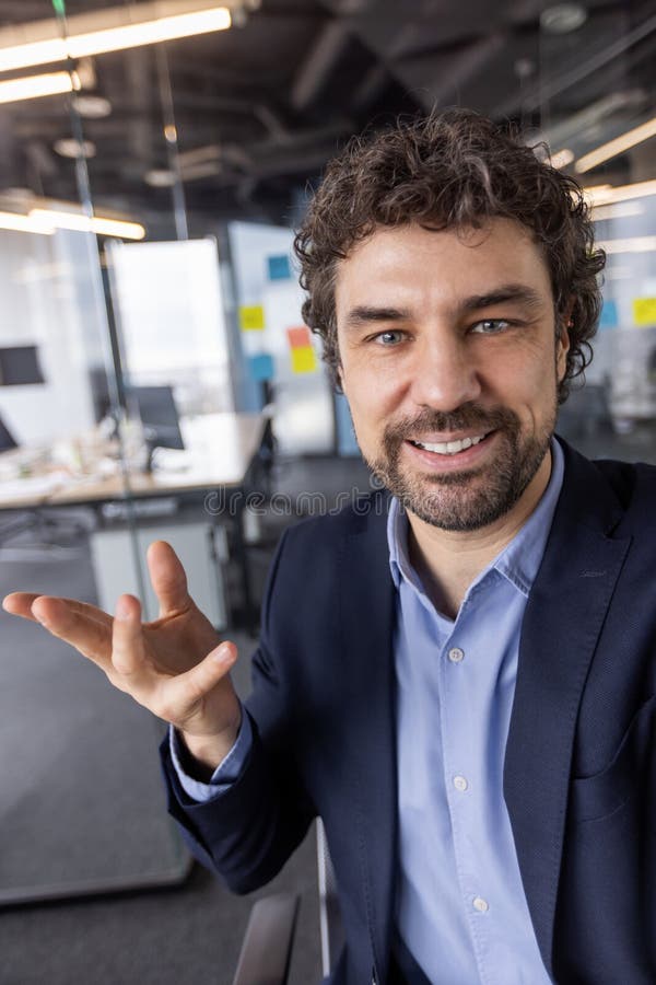 Smiling Businessman on Video Call in Modern Office Space Looking at ...