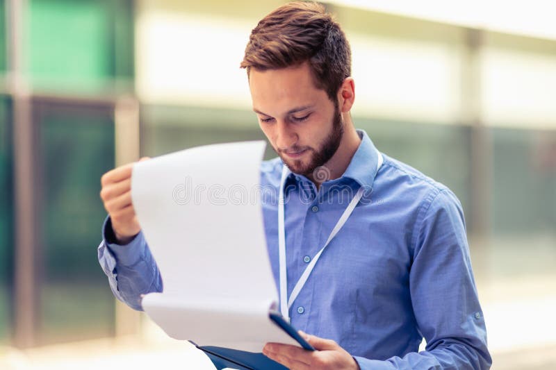 Businessman Outdoors Looking at Business Documentation. Stock Photo ...